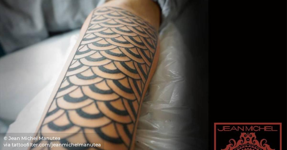 Patterned rectangle tattoo on the left inner forearm.