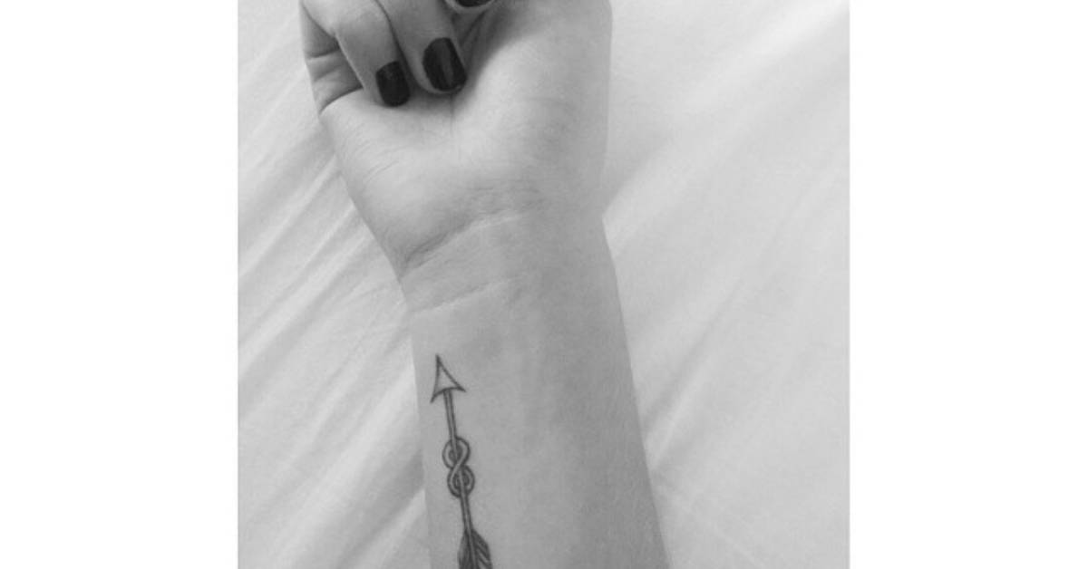 Little forearm tattoo of an arrow crossing the infinity