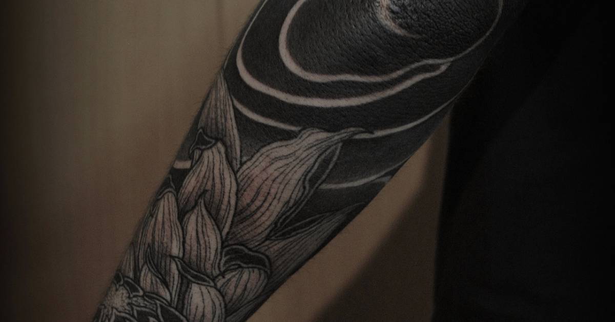 Blackwork style sleeve tattoo on the left arm.