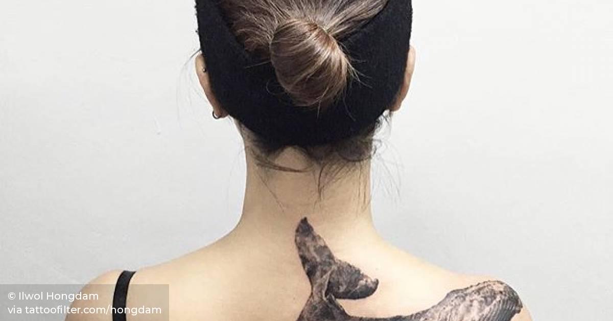 Illustrative whale tattoo on the upper back and