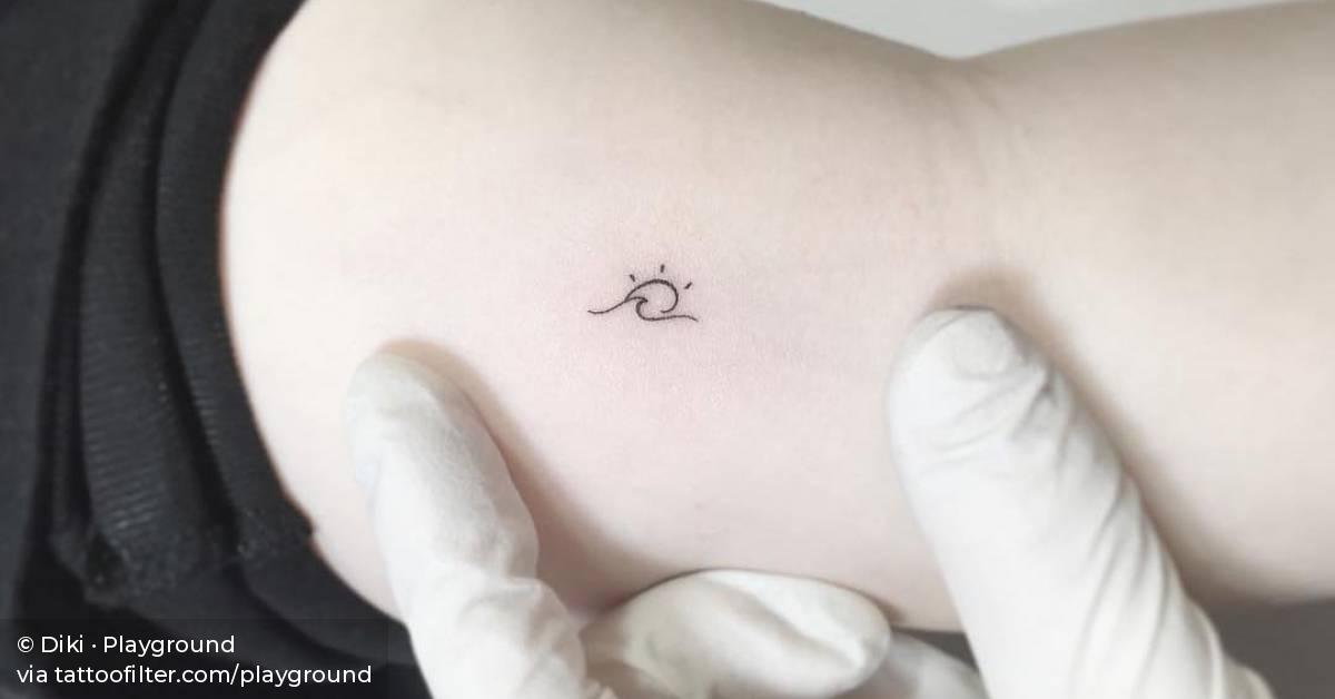 Wave and sun tattoo on the inner arm.