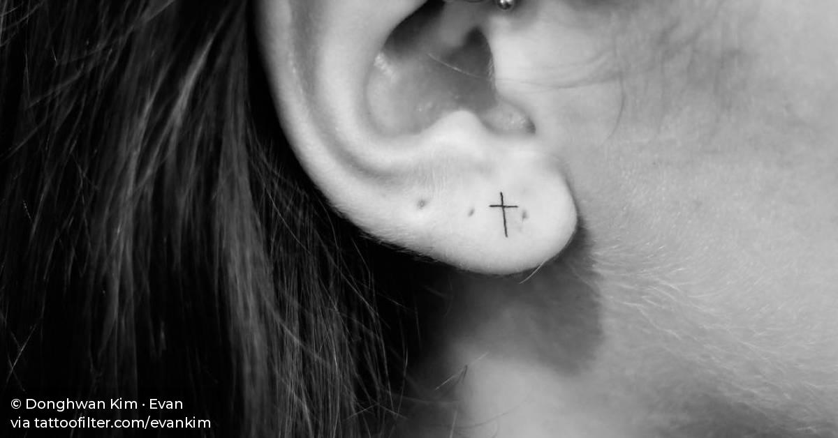Small Christian cross tattoo on the ear.