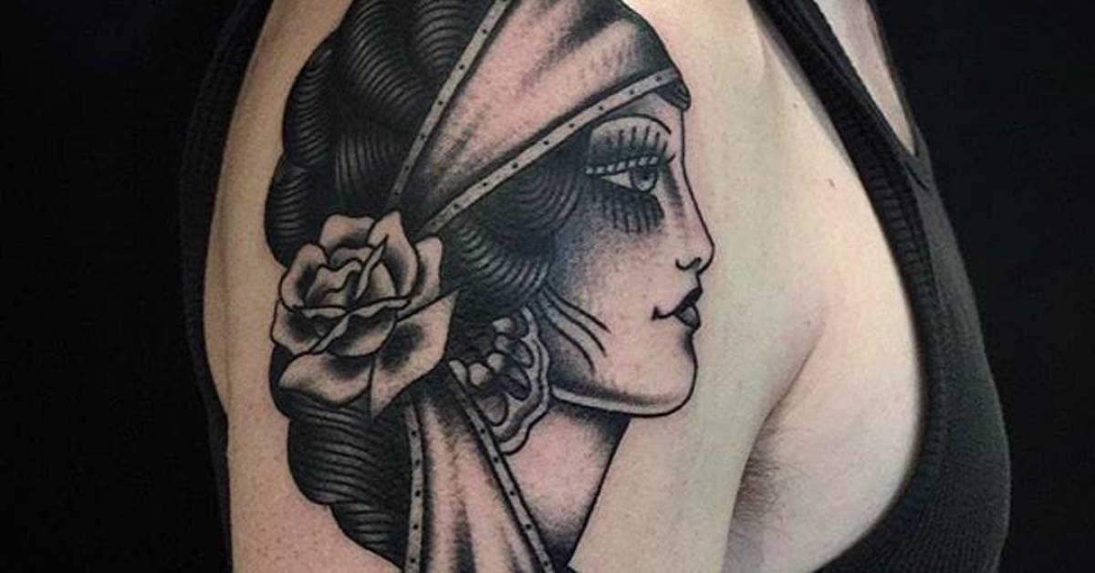 Traditional style lady head tattoo on the upper arm.
