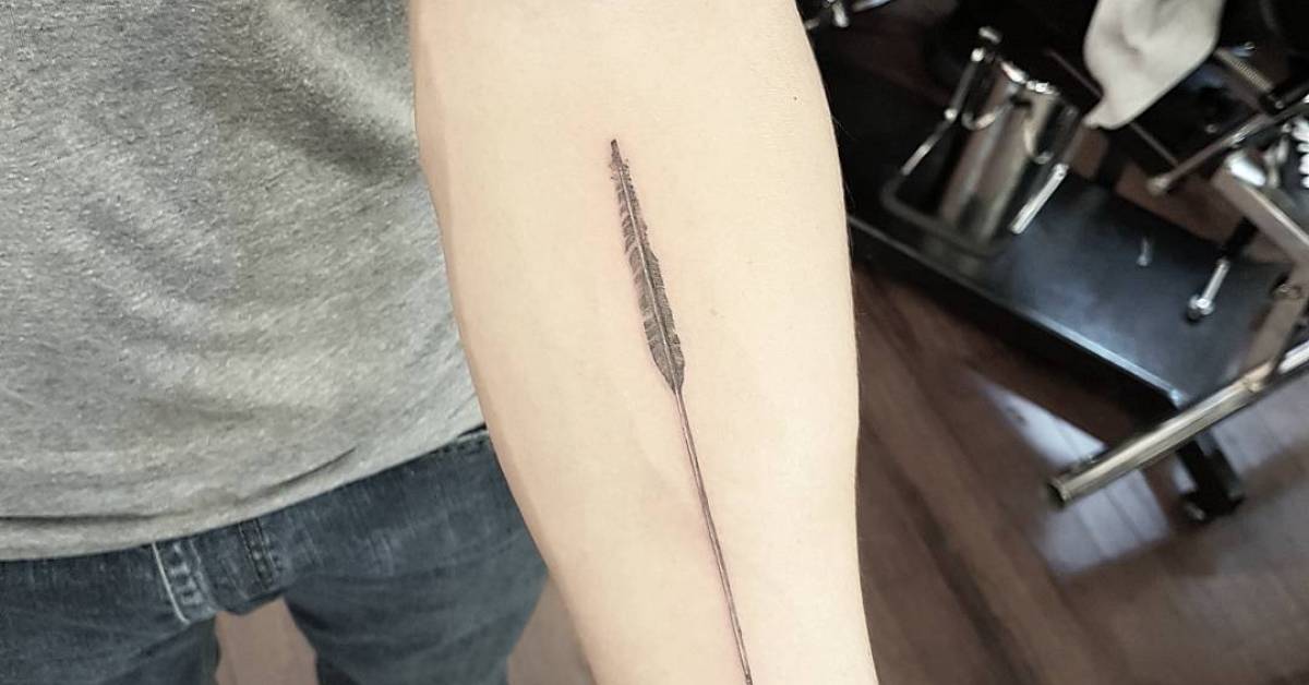 Fine line style arrow tattoo on the left inner forearm.