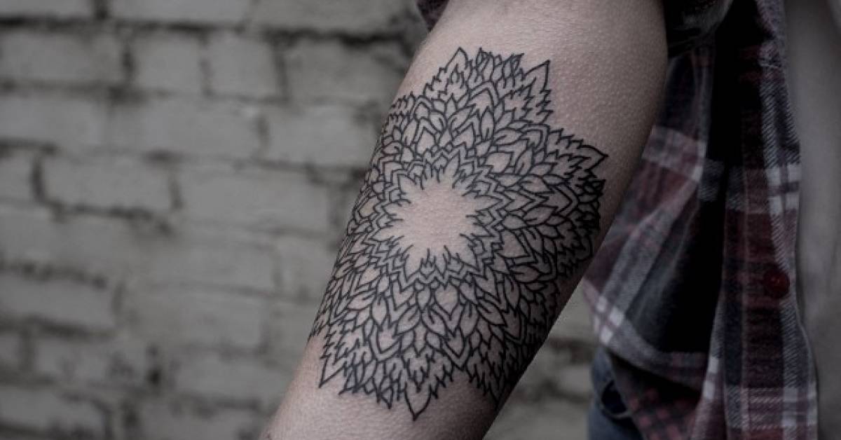 Ornamental mandala tattoo on the inner forearm.