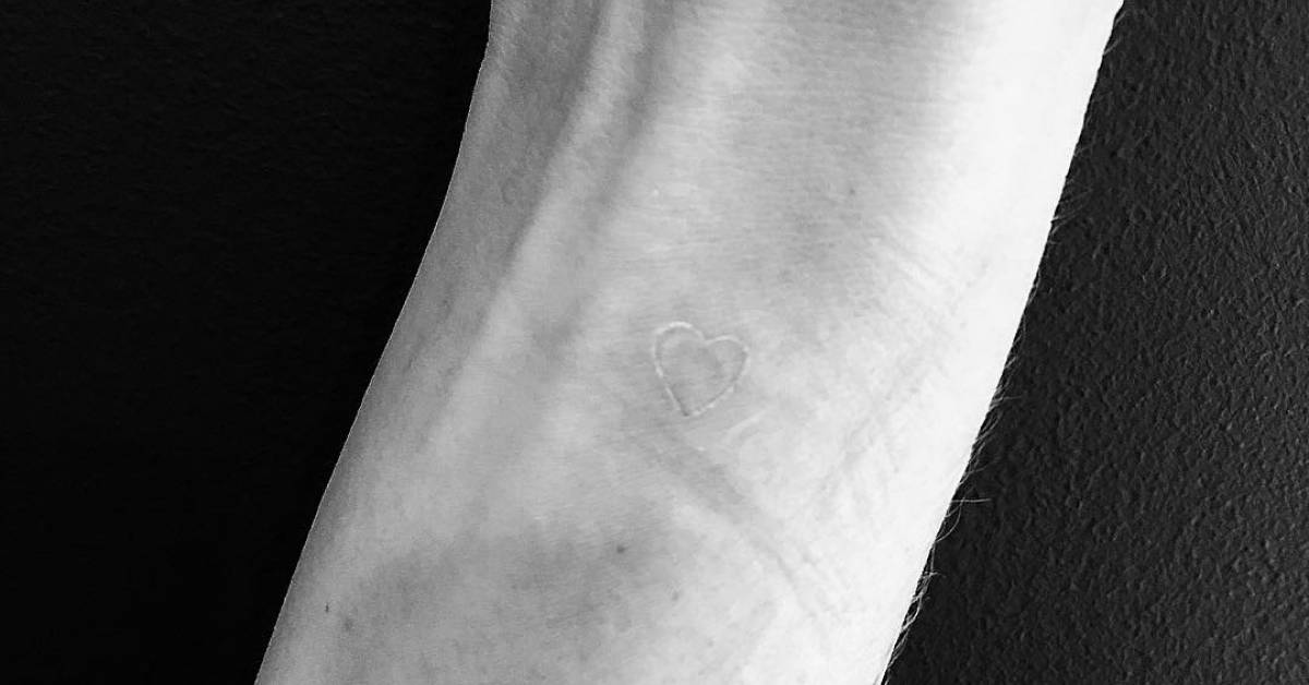 White ink heart tattoo on the inner wrist.