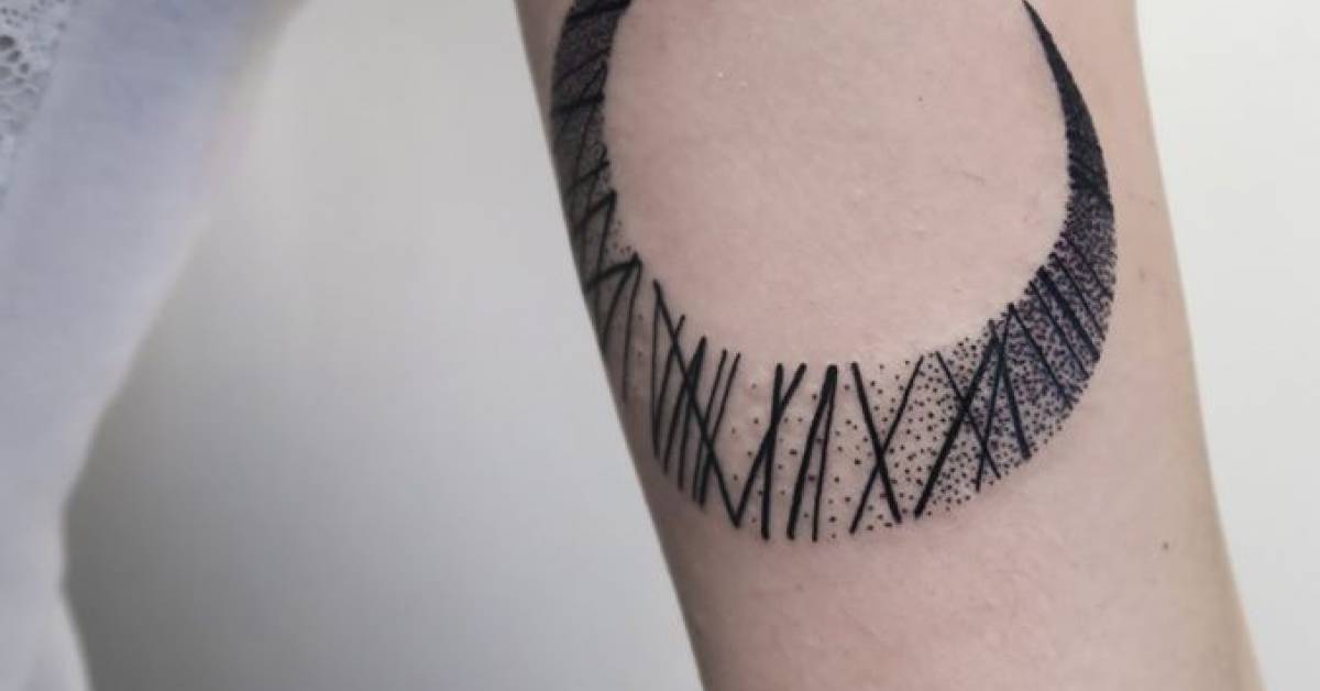 Abstract crescent moon tattoo on the left inner arm.