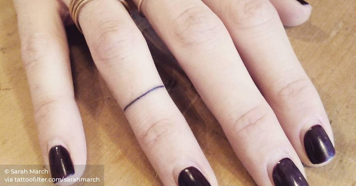 Minimalist ring tattoo on the right ring finger.