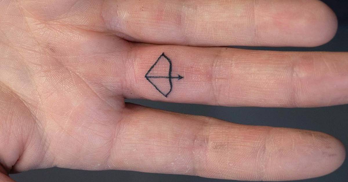 Small bow and arrow tattoo on the finger.