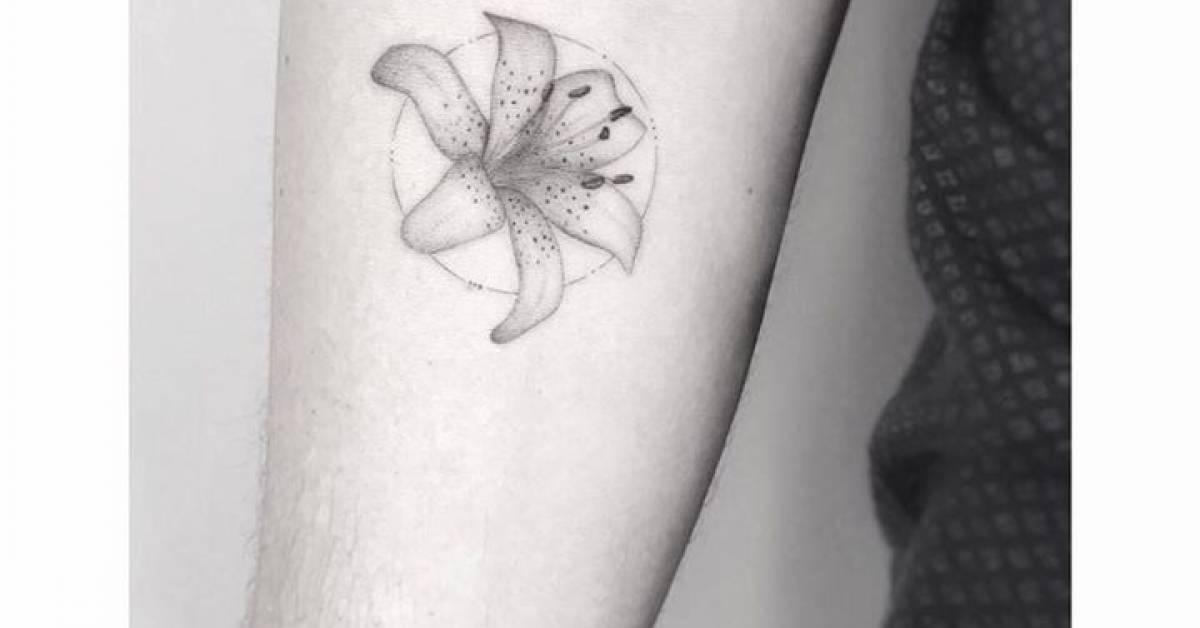 Fine line lily tattoo on the right inner forearm.