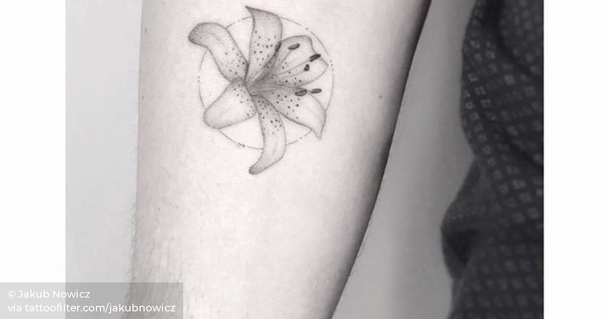 Fine line lily tattoo on the right inner forearm.