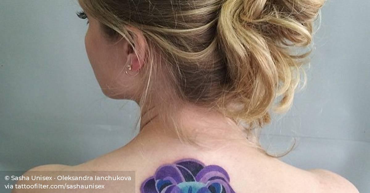 Purple lion head tattoo on the upper back.