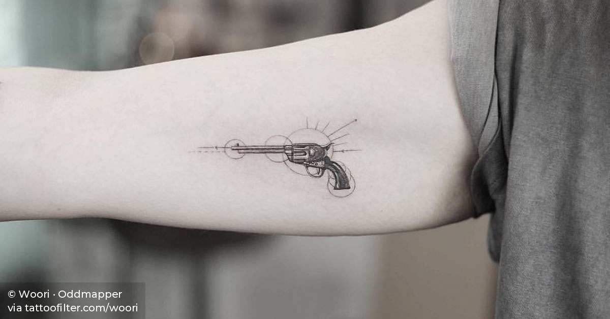Fine line revolver tattoo on the right inner arm.