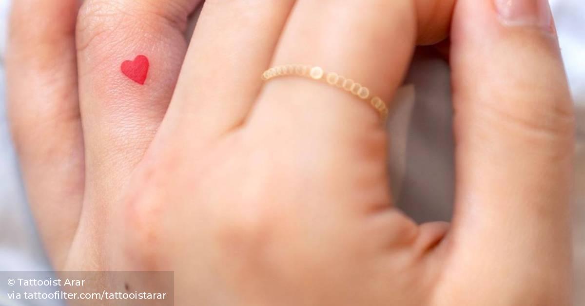 Small red heart tattoo on the left ring finger.