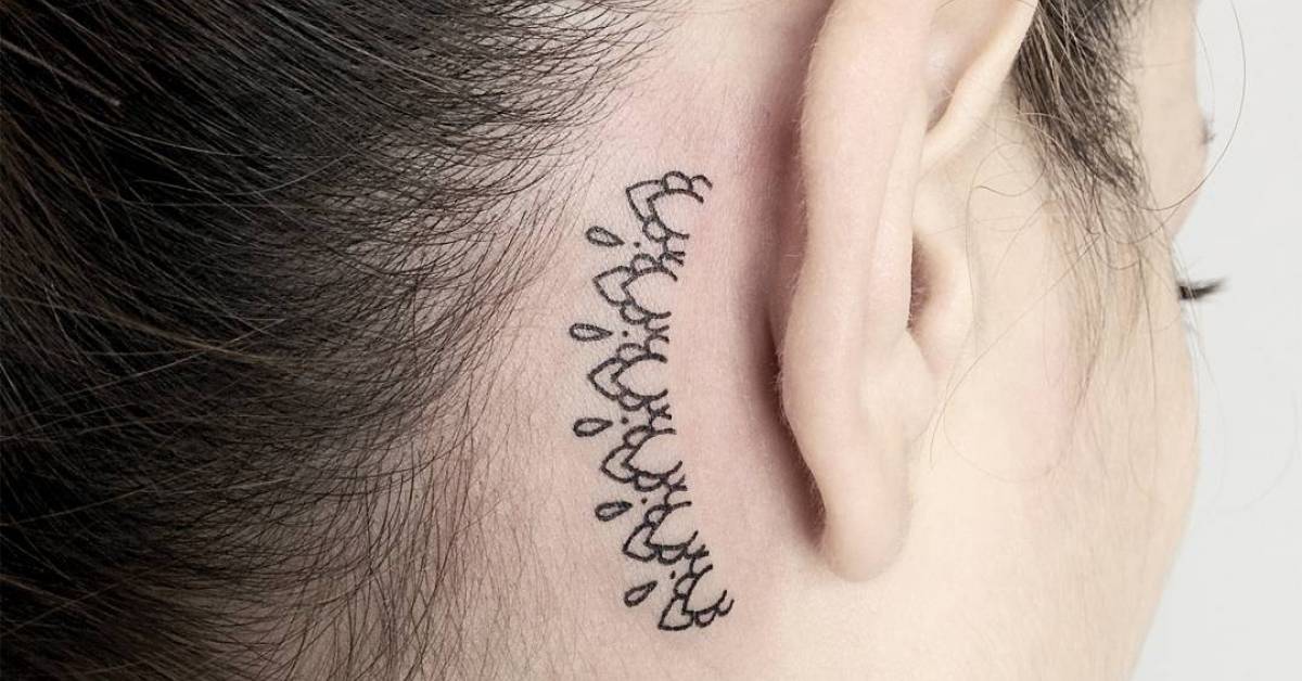 Fine ornamental tattoo behind the right ear.