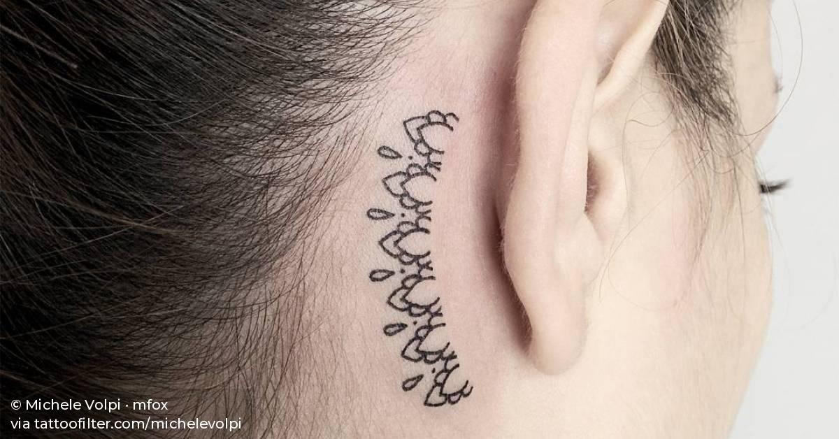 Fine ornamental tattoo behind the right ear.