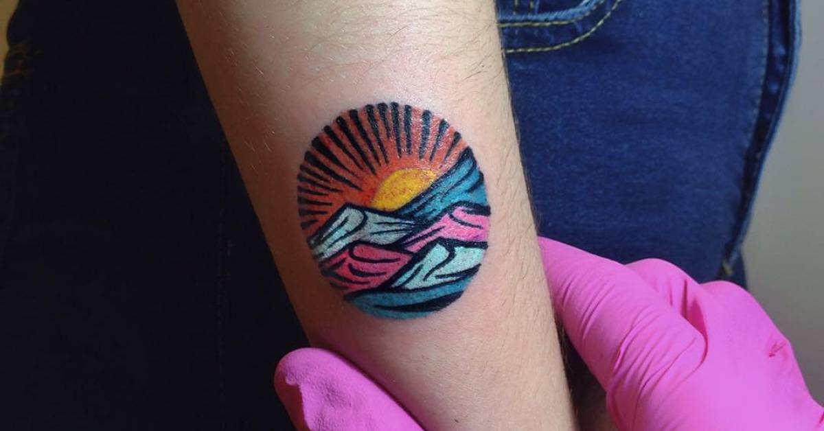 Linocut style landscape tattoo on the right forearm.