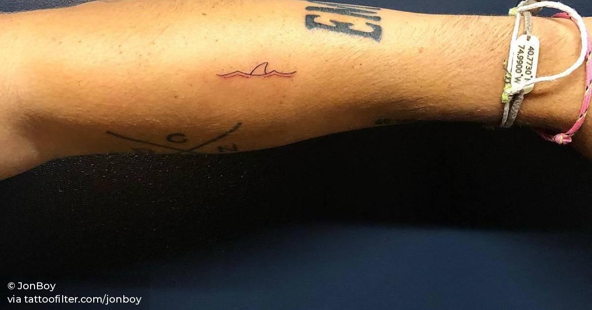 Shark fin tattoo on the forearm.