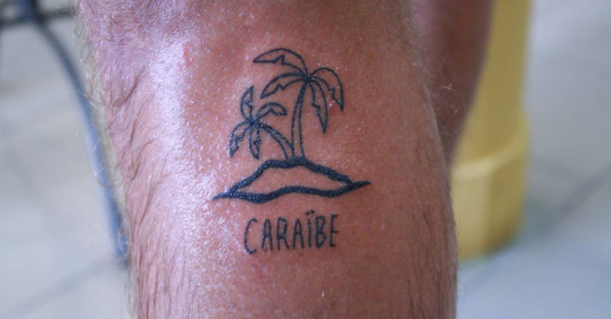 Calf tattoo saying "Caraïbe" together with an island
