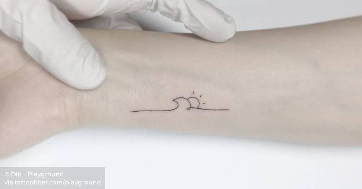 Sun and wave tattoo on the wrist.