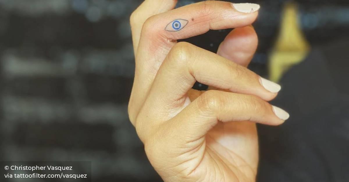 Evil eye tattoo on the right middle finger.