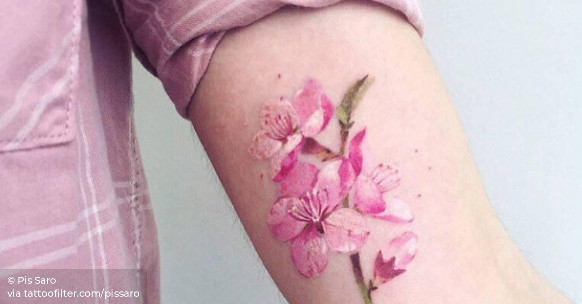 Cherry blossom branch tattoo on the left inner arm.