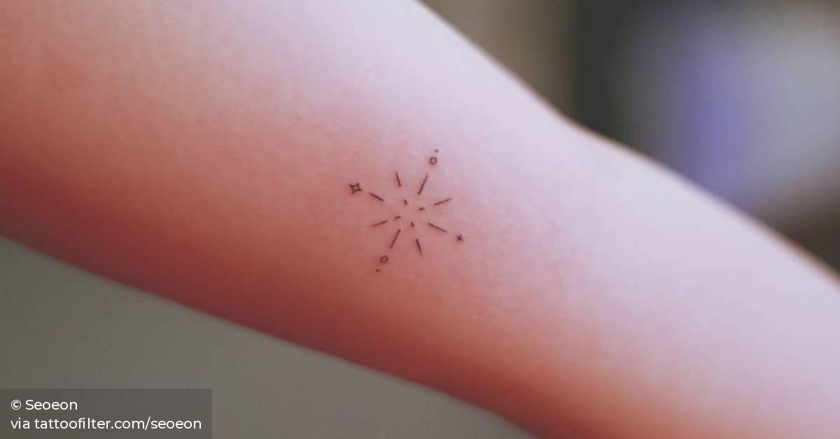 Minimalist star tattoo on the left inner arm.