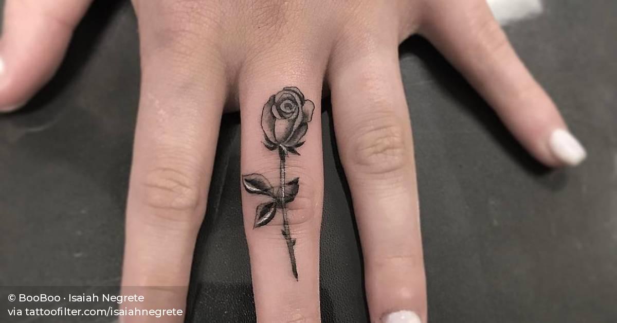 Fine line rose tattoo on the middle finger.
