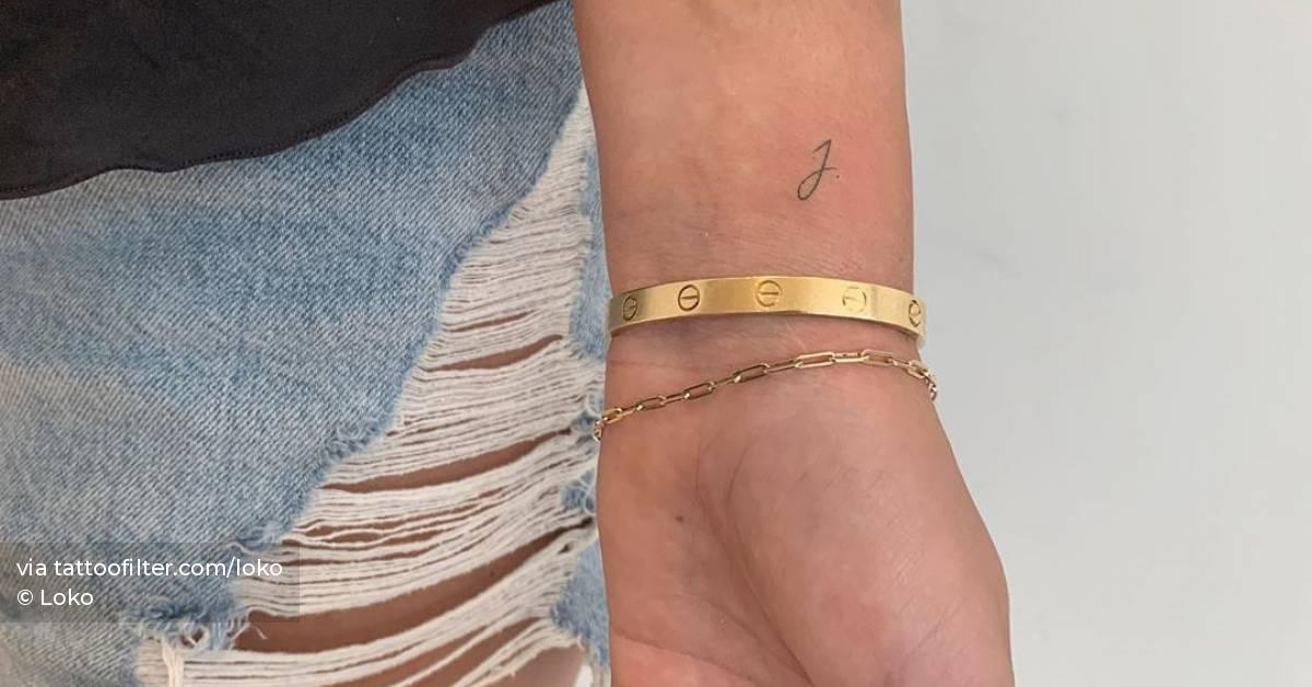 "J" minimalist lettering tattoo on wrist