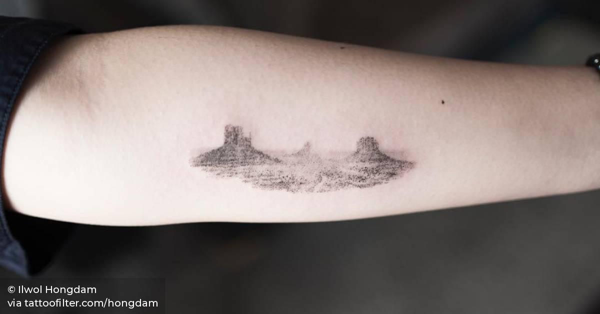 Monument Valley tattoo on the left inner forearm.