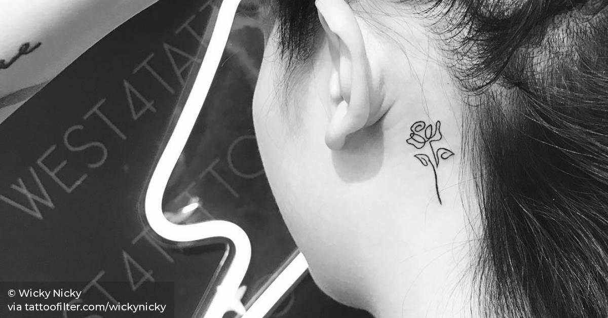 Fine line rose tattoo behind the left ear.