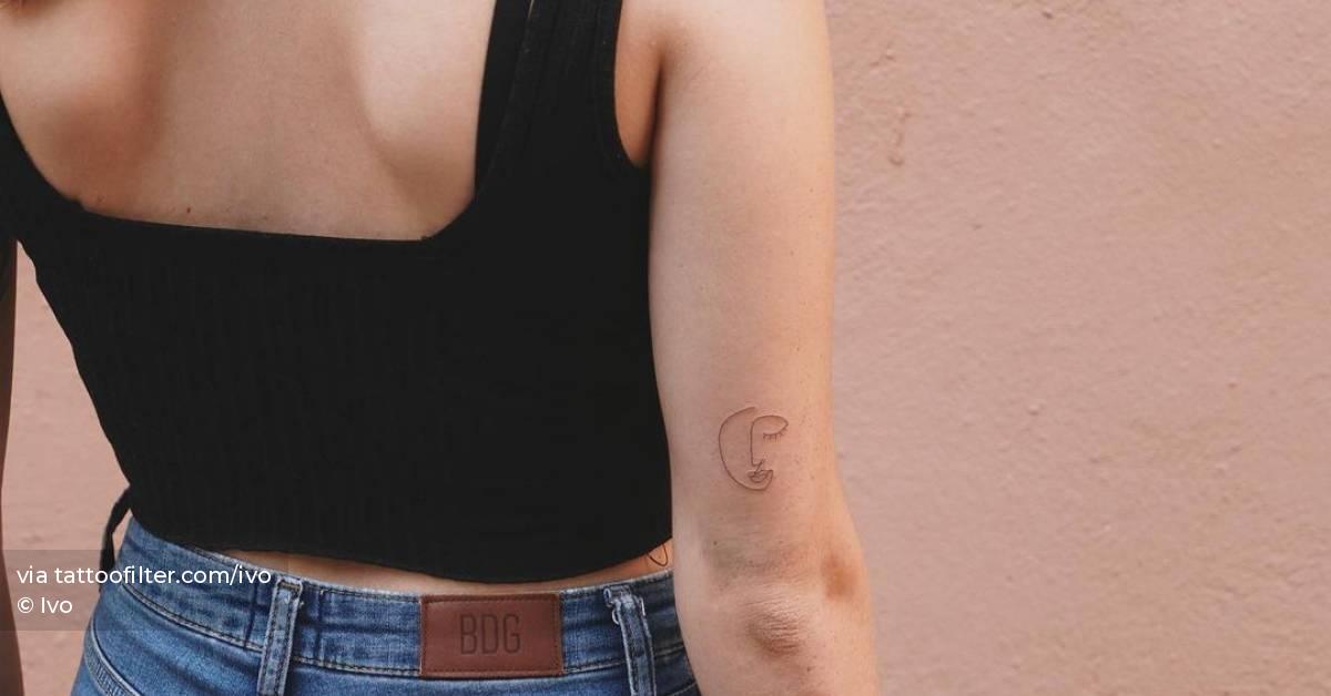 Minimalist face tattoo on the tricep.