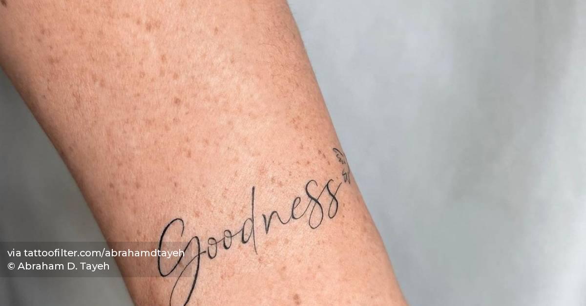 "Goodness" lettering tattoo on the inner forearm.