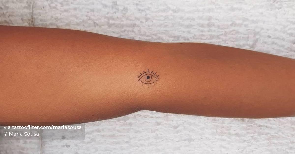 Minimalist evil eye tattoo on the elbow.
