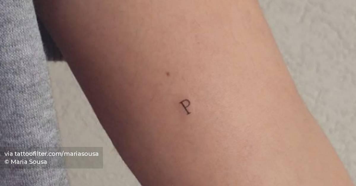 Minimalist letter "P" tattoo on the inner forearm.