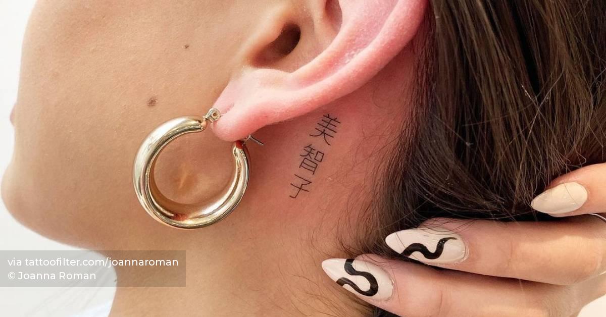 Kanji lettering tattoo behind the ear.