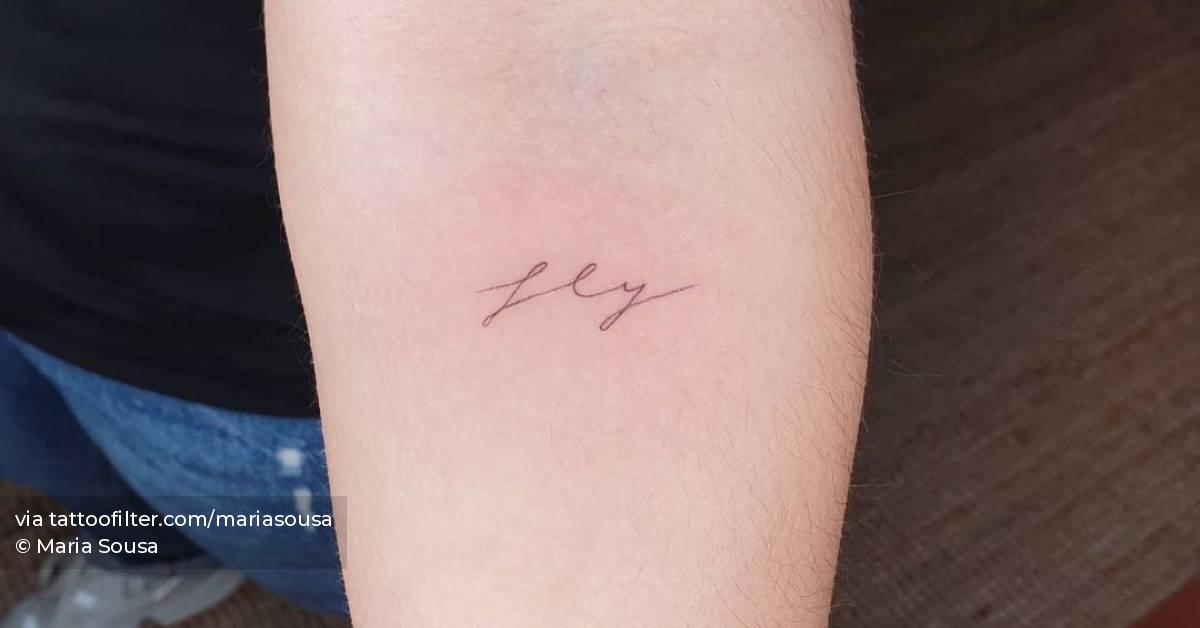 "Fly" lettering tattoo on the inner forearm.