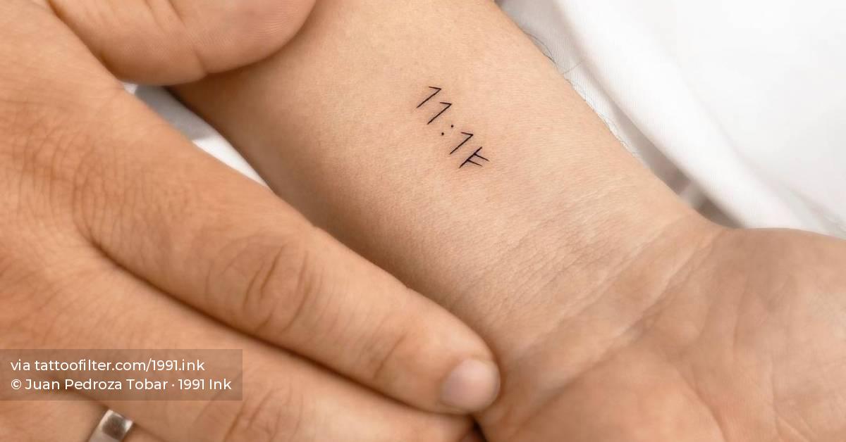 "11:11" lettering tattoo on the wrist.