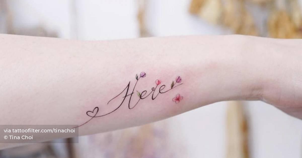 "Here" lettering tattoo on the wrist.