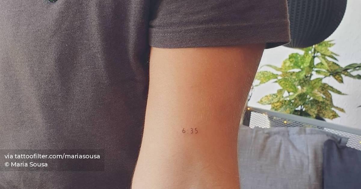 "6:35" lettering tattoo on the bicep.