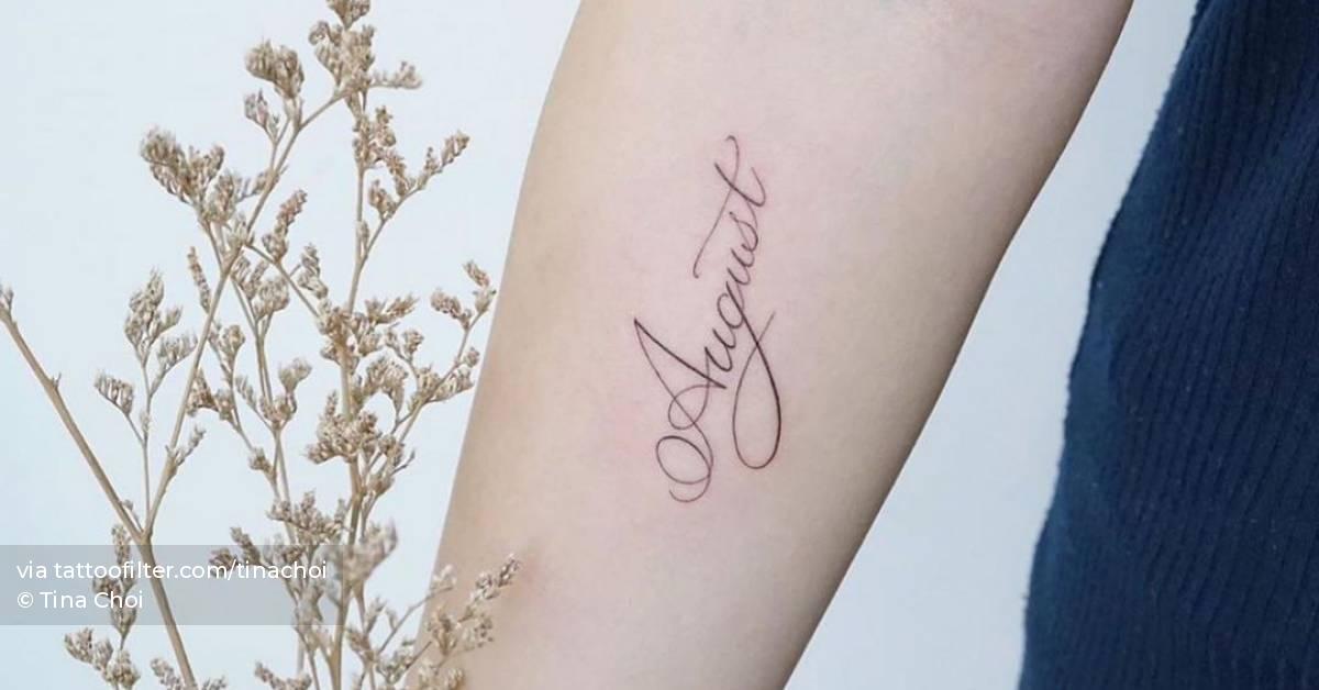 "August" lettering tattoo on the inner forearm.