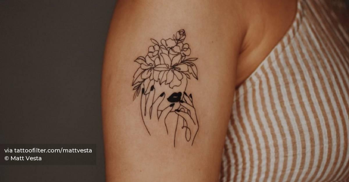 Flower head woman tattoo on the upper arm.