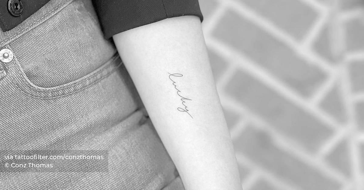 "Lucky" lettering tattoo on the forearm.