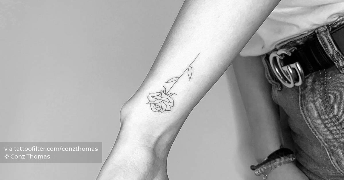 Fine line rose tattoo on the wrist.