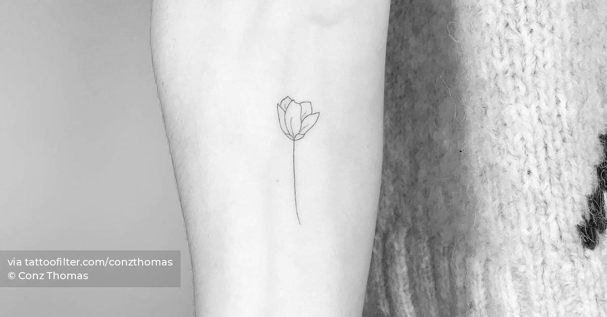 Fine line flower tattoo on the inner forearm.