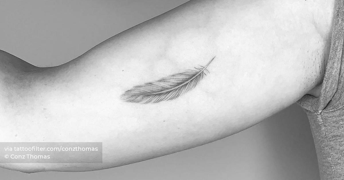 Fine line feather tattoo on the inner arm.