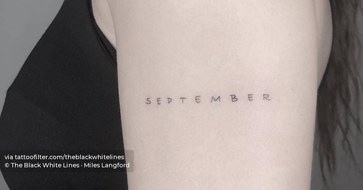 "September" lettering tattoo on the upper arm.