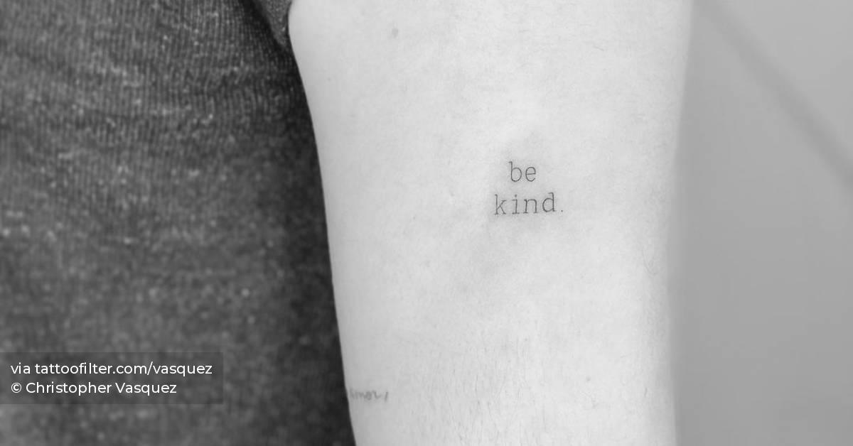 "Be kind" lettering tattoo on the upper arm.
