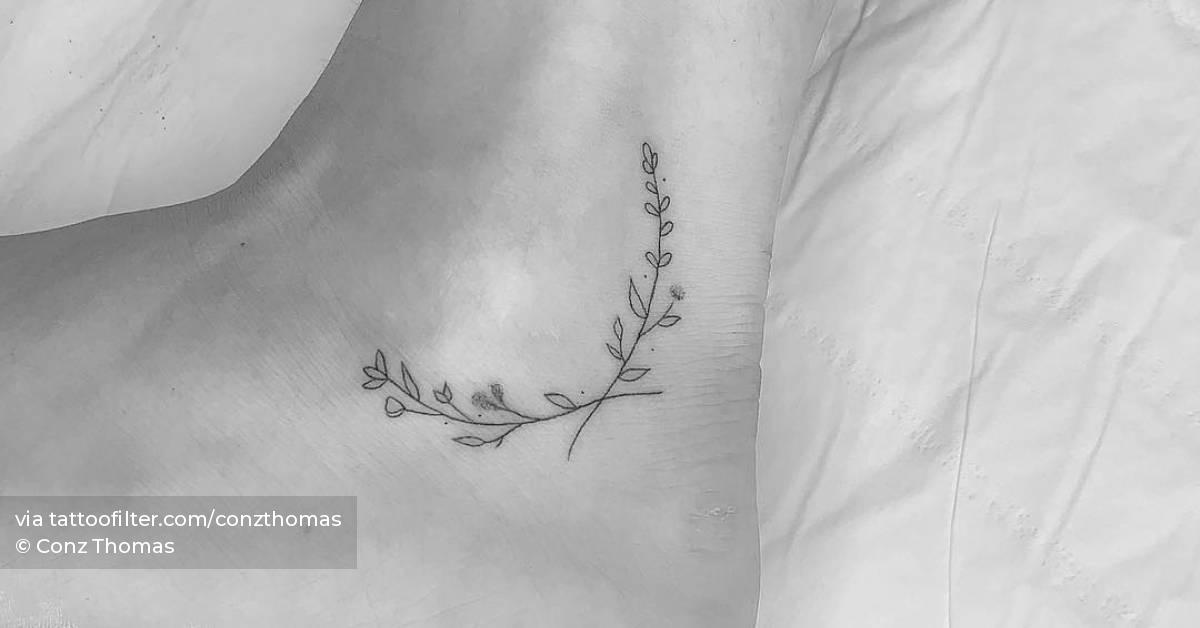 Fine line laurel wreath tattoo on the ankle.