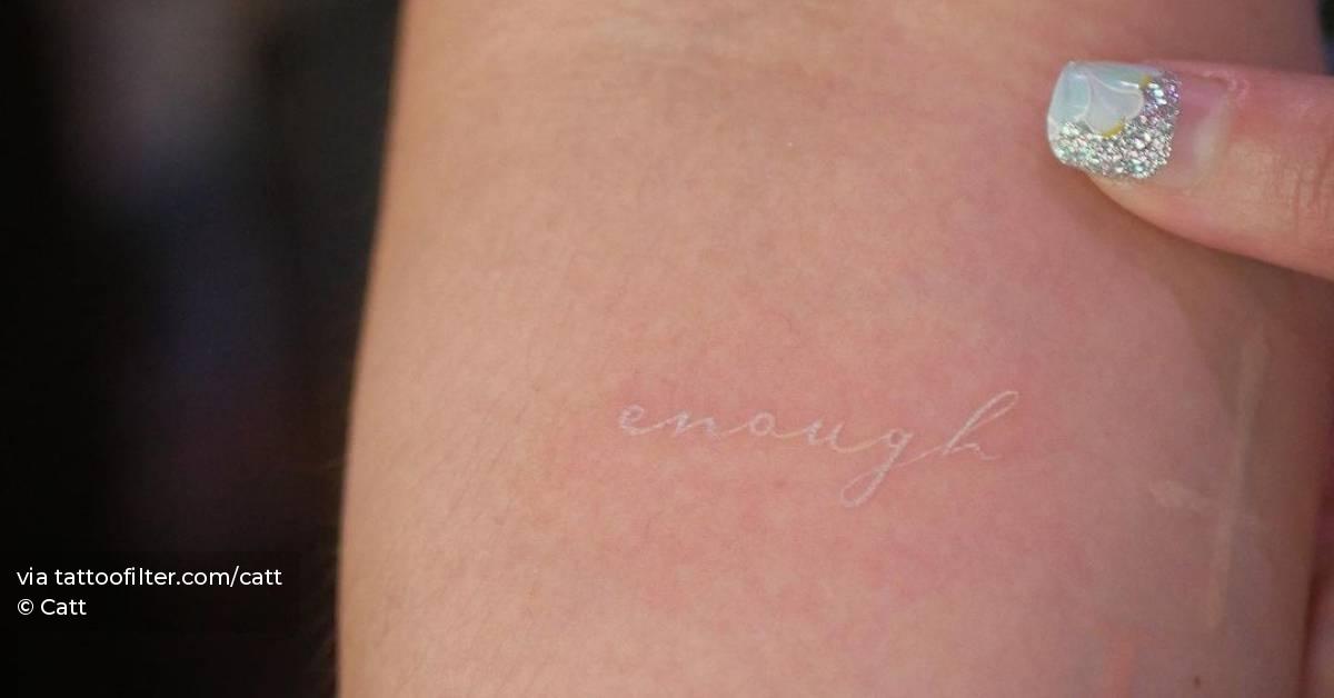 "Enough" lettering tattoo on the inner forearm.
